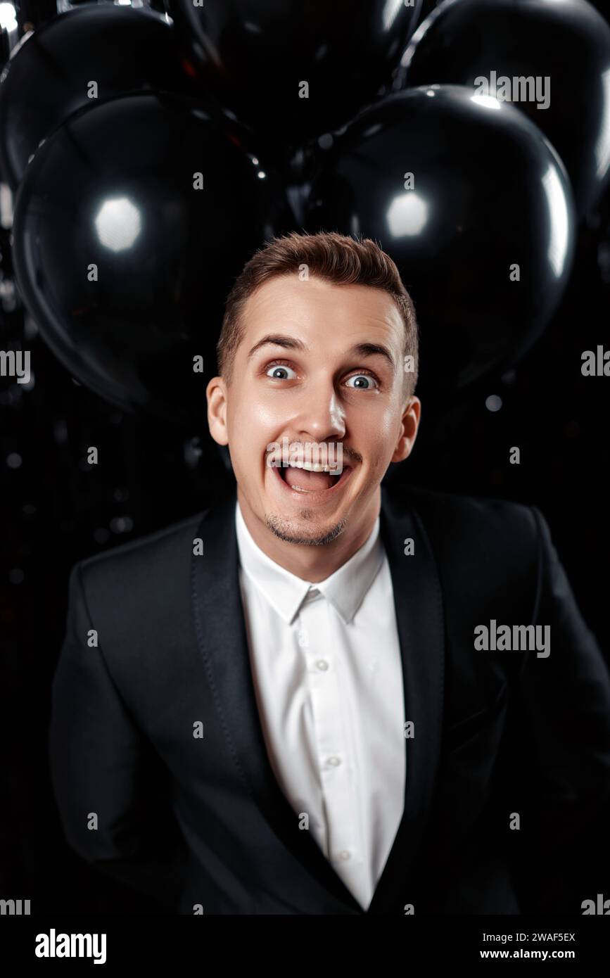 very excited guy in black jacket holding black air balloons on glitter ...