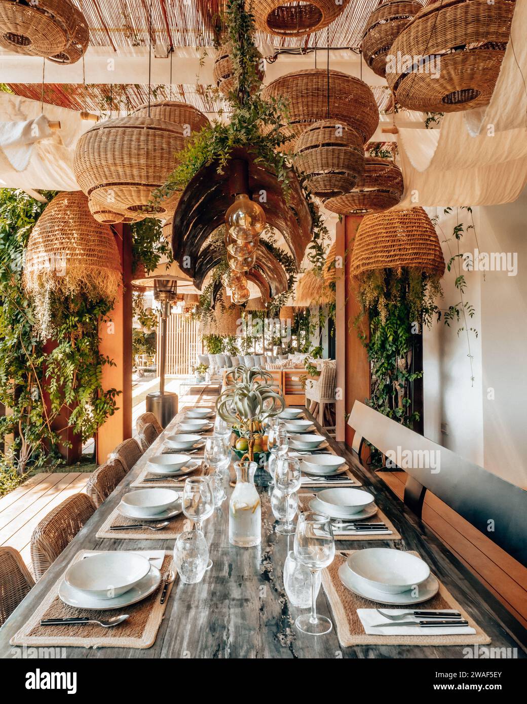 An outdoor dining area featuring a long wooden table with white ...