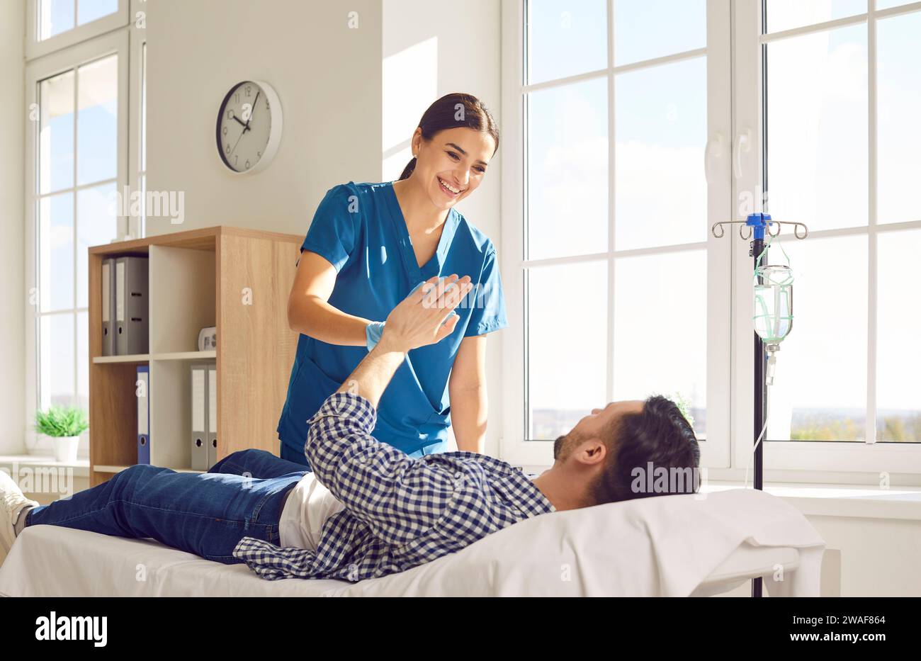 Nurse giving high five to man receiving IV drip infusion and vitamin ...