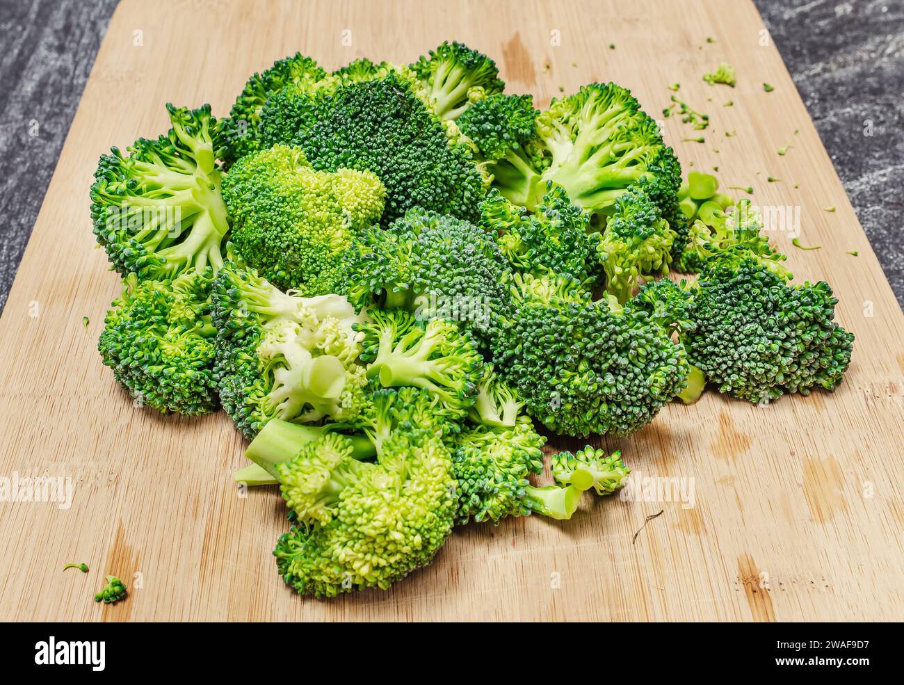 Fresh green broccoli divided into florets on wooden board. Appetizing ...
