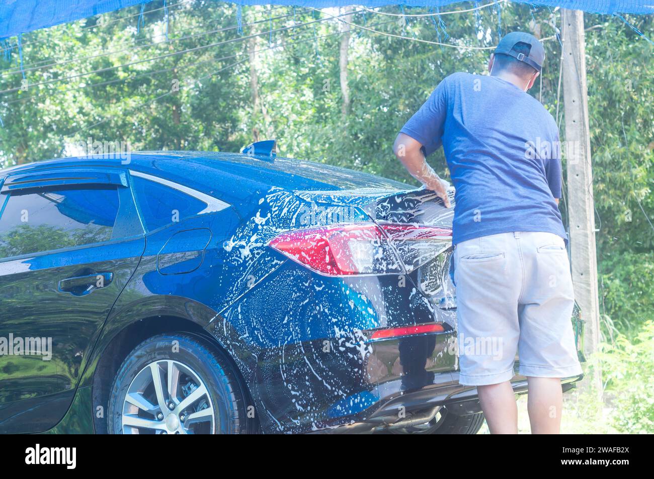 Staff or car washer at car care service center is washing a car of ...