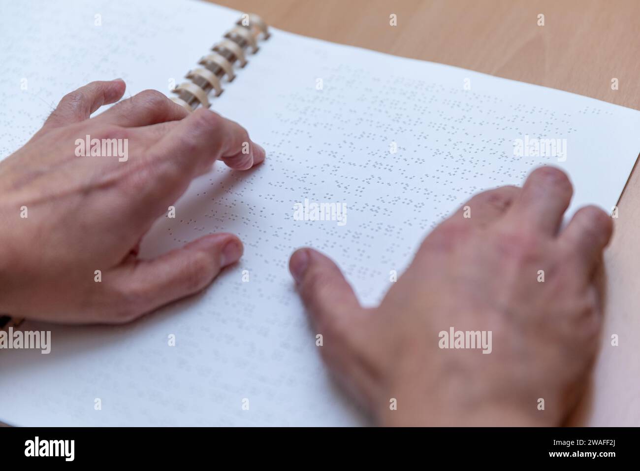 Blind or visually impaired person reading a book printed with braille ...