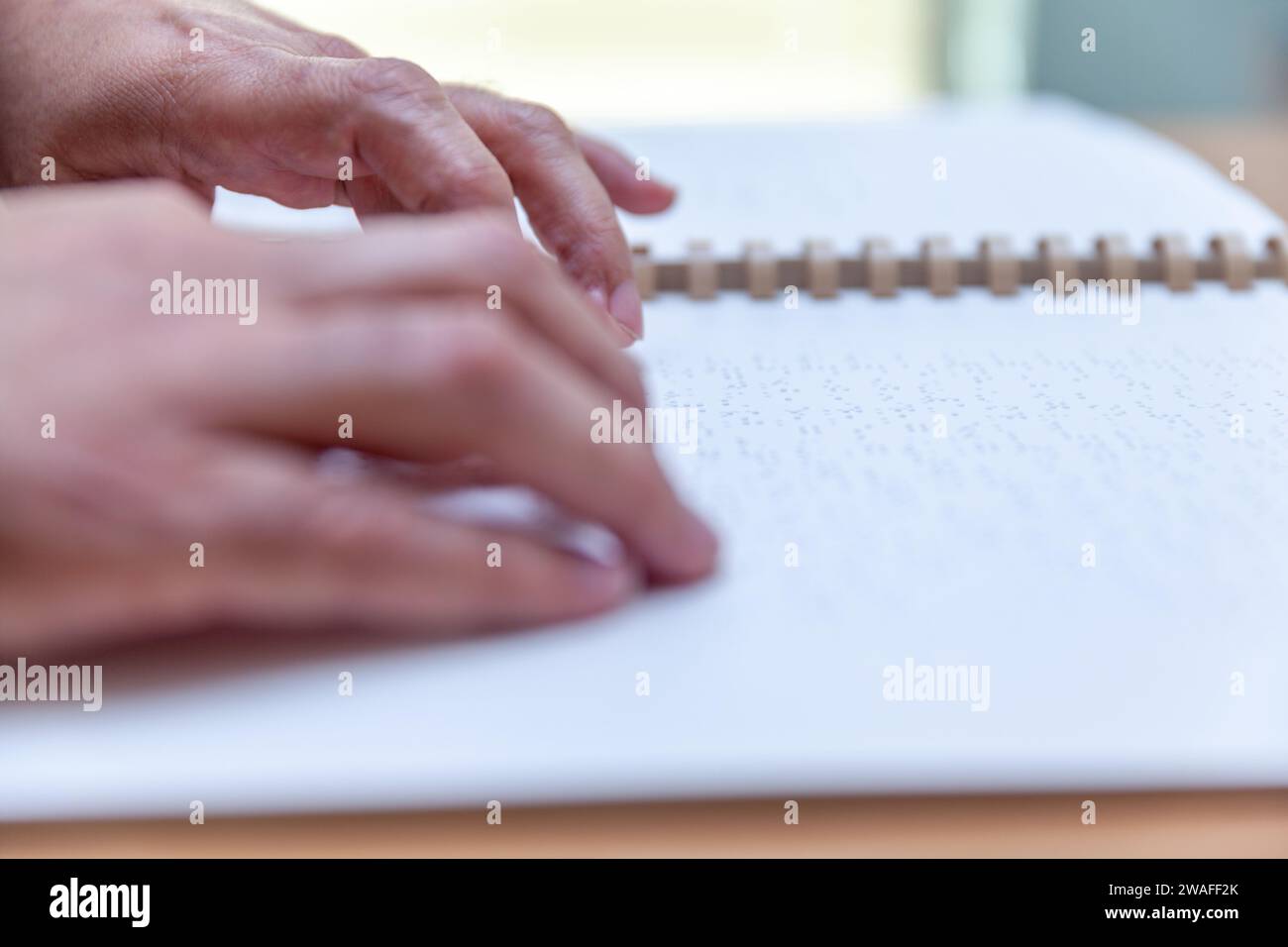 Blind or visually impaired person reading a book printed with braille ...