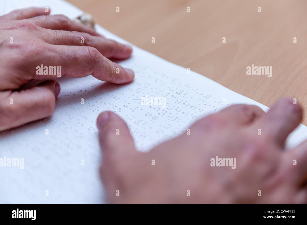 Blind or visually impaired person reading a book printed with braille ...