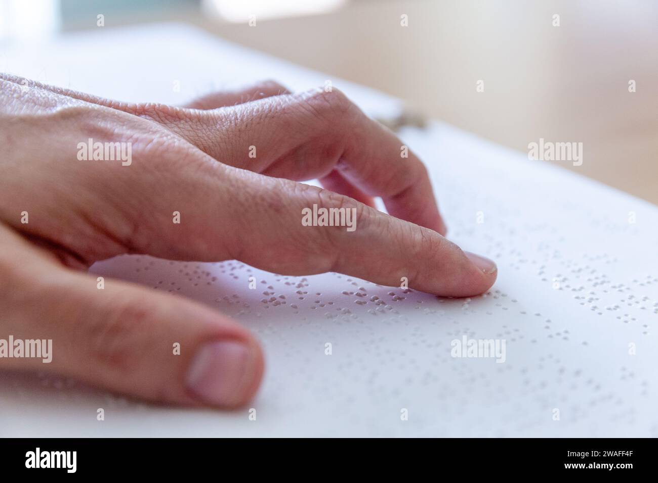Blind or visually impaired person reading a book printed with braille ...