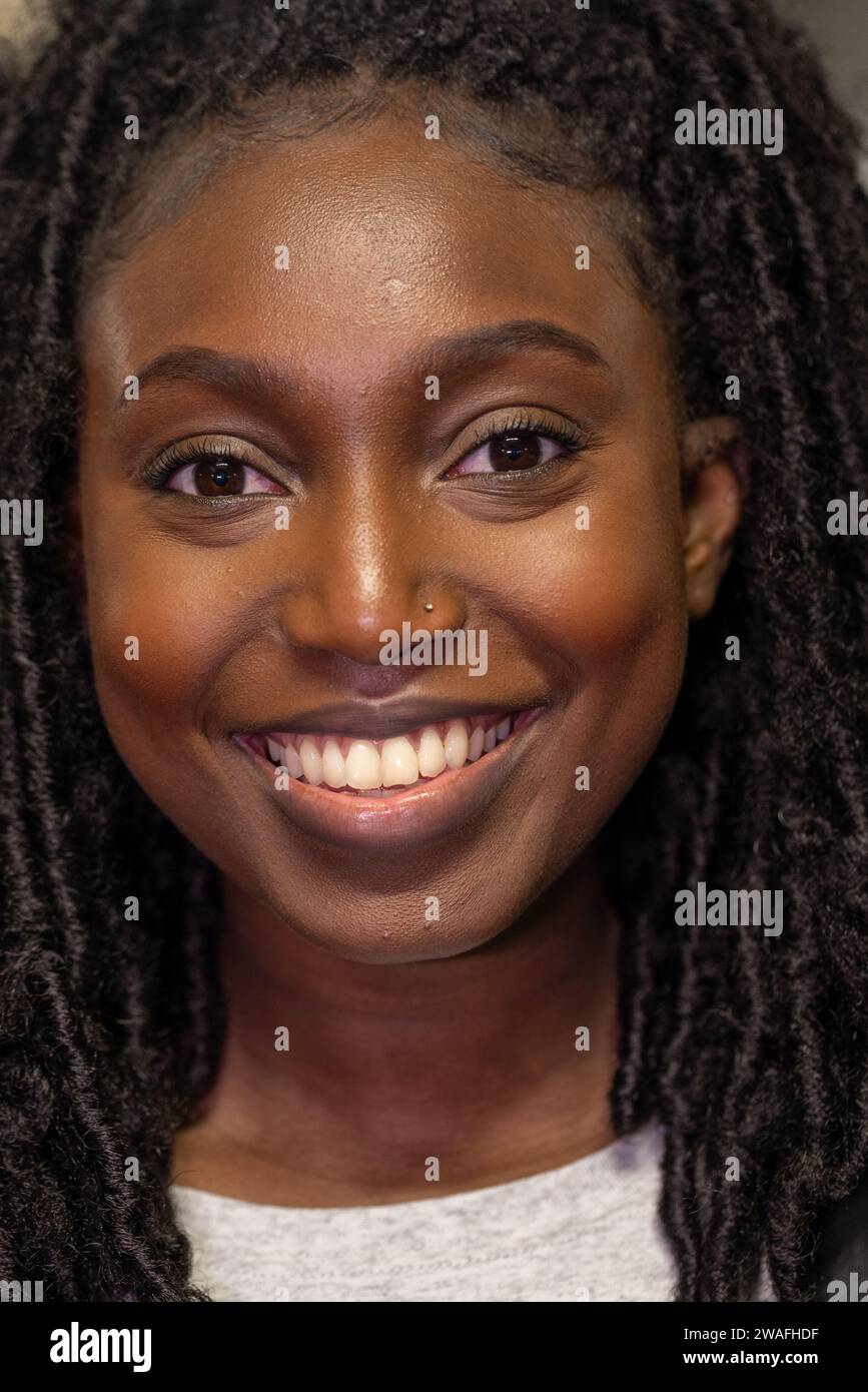 This portrait features a young Black woman with a radiant, open smile ...