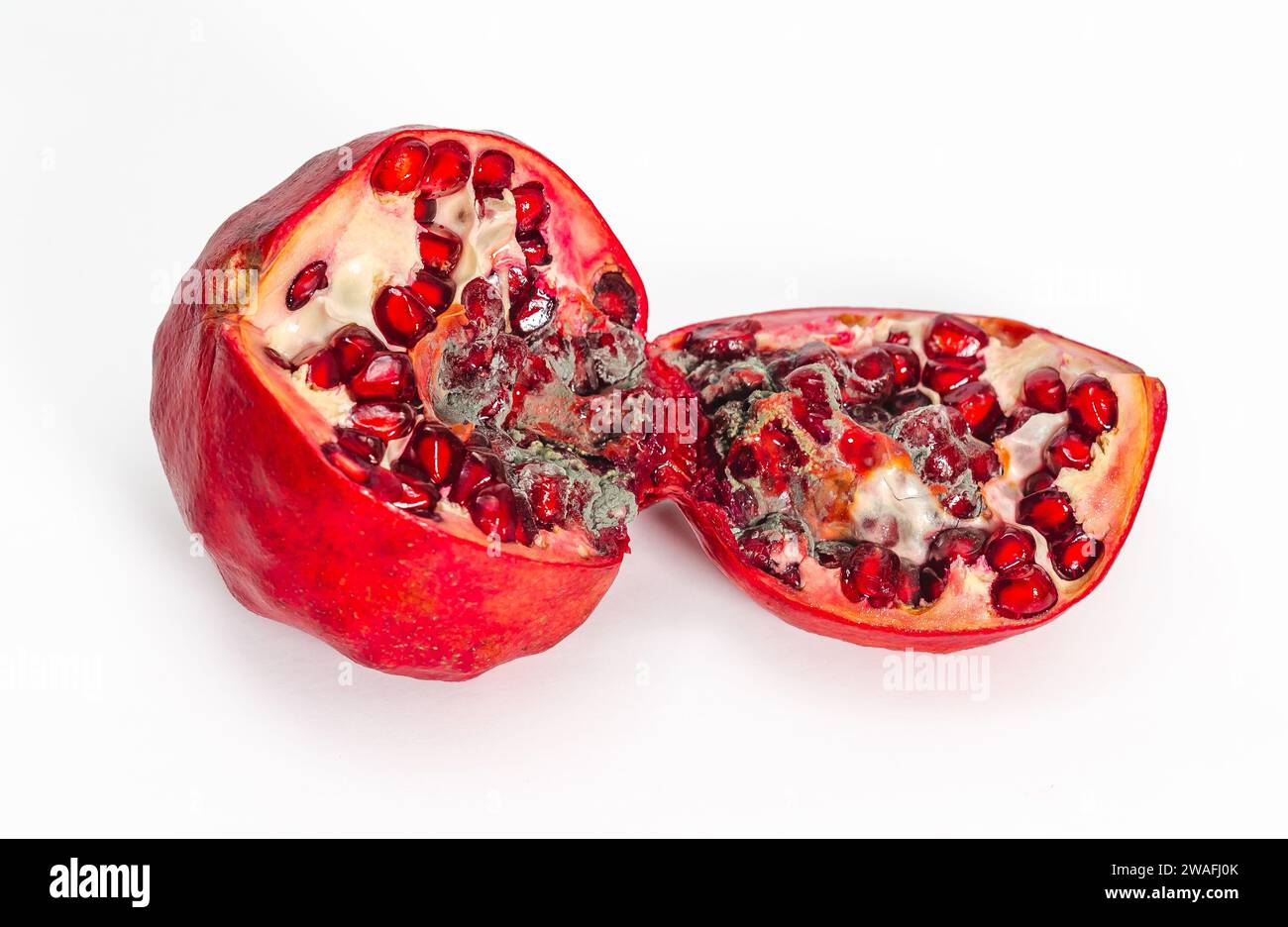Spoiled red pomegranate with mold. Cut into two pieces. White ...