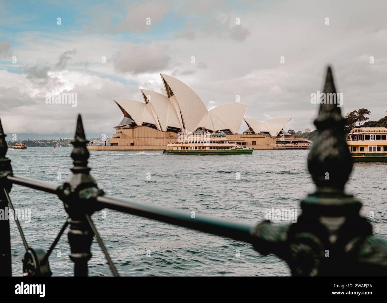 A vibrant view of the iconic opera house across a tranquil body of ...