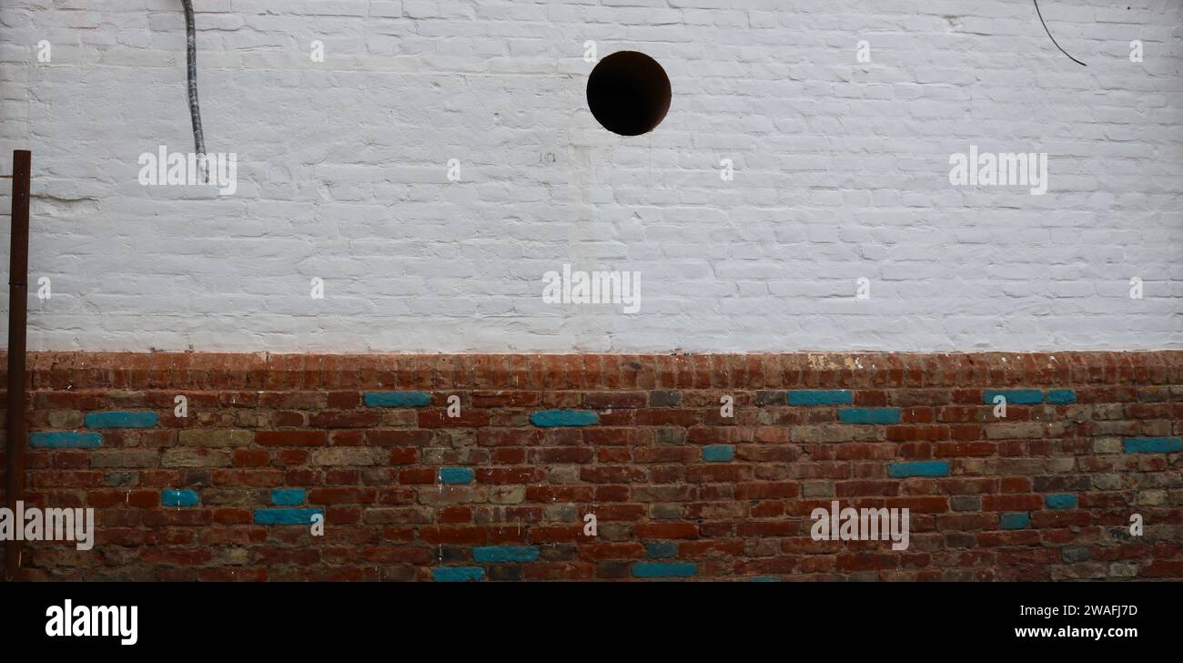 fragment of a brick wall of a building whitewashed on top and red with ...