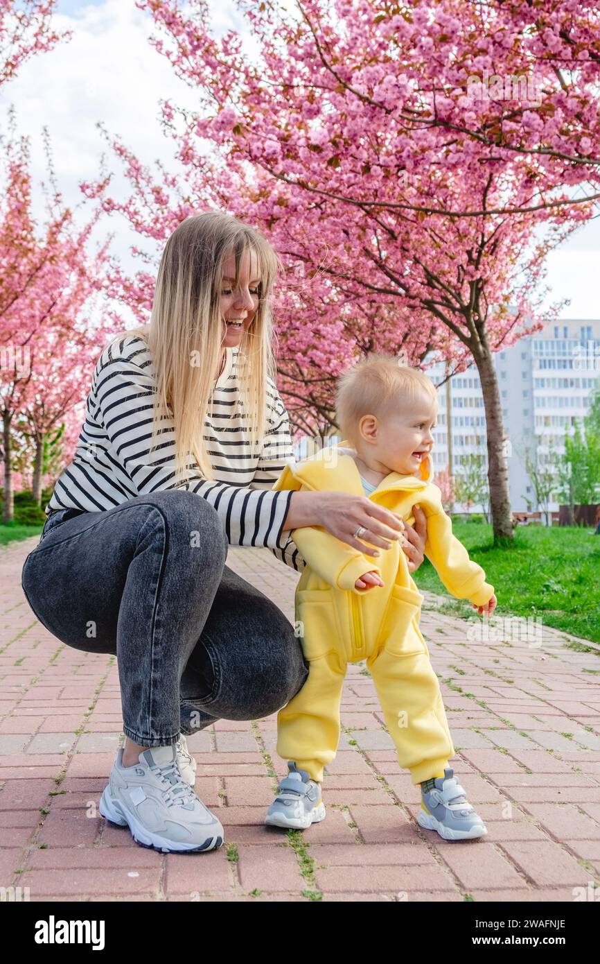 baby boy learns to walk holding his mother's hands Stock Photo - Alamy
