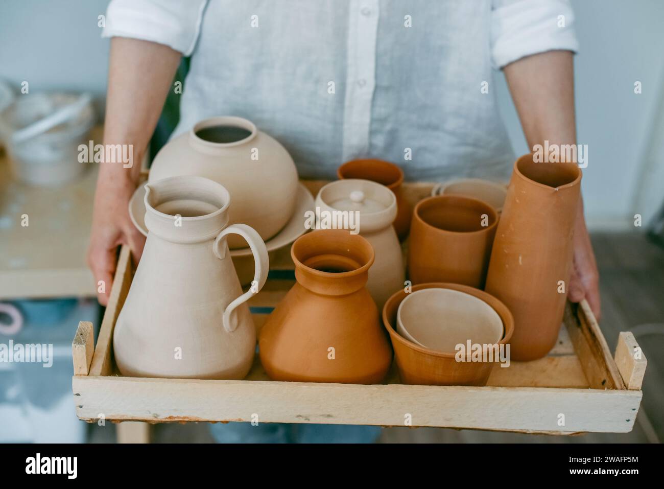 Woman master of pottery workshop carries clay products for firing Stock ...