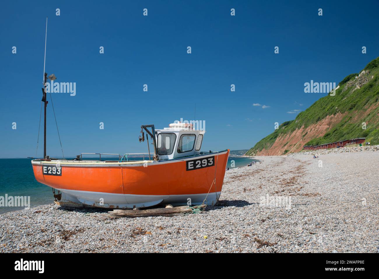 Orange fishing boat sitting on the shingle of Branscombe Mouth Beach, Devon, England Stock Photo ...