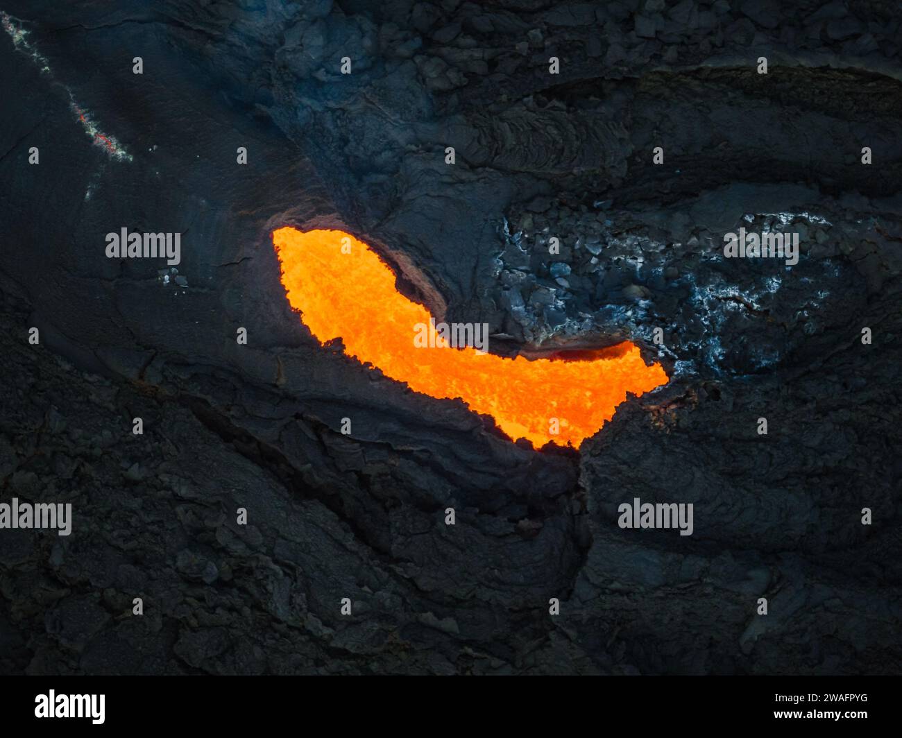 Boiling red hot magma fast flowing through lava tubes under a layer of ...