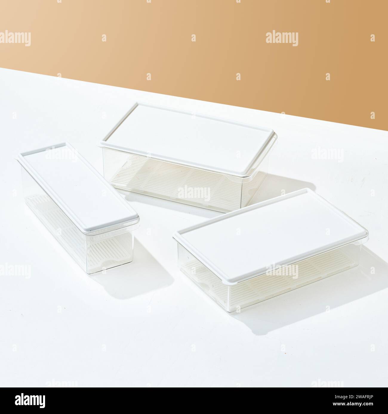 A plain transparent plastic food container, on a white and beige ...