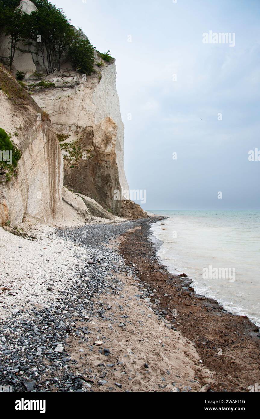 White limestone cliffs with green vegetation along a gravel beach on ...