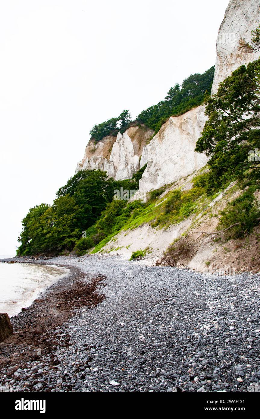 White limestone cliffs with green vegetation along a gravel beach on ...