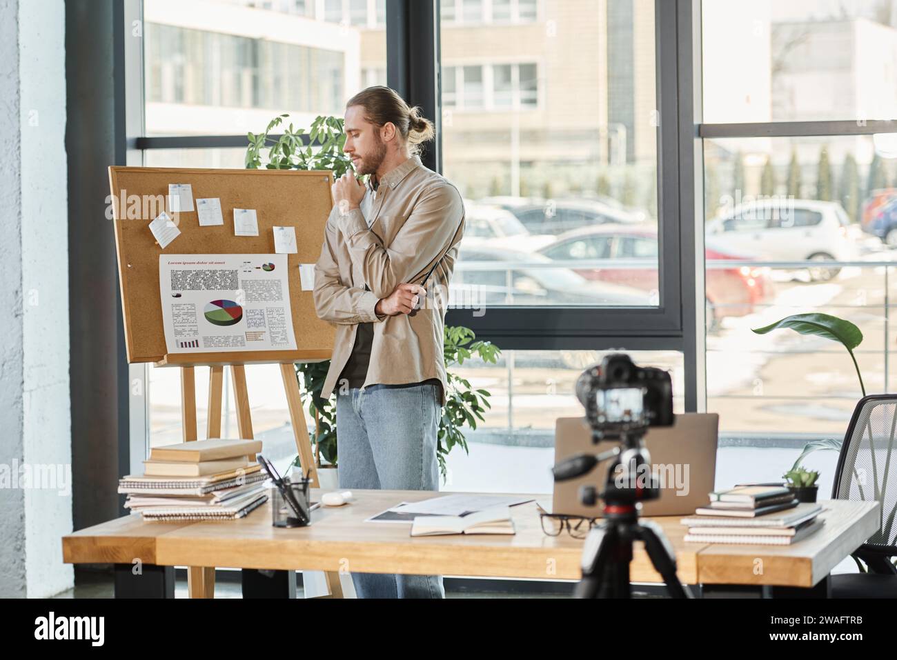 thoughtful businessman looking at flip charts with infographics near digital camera in office ...