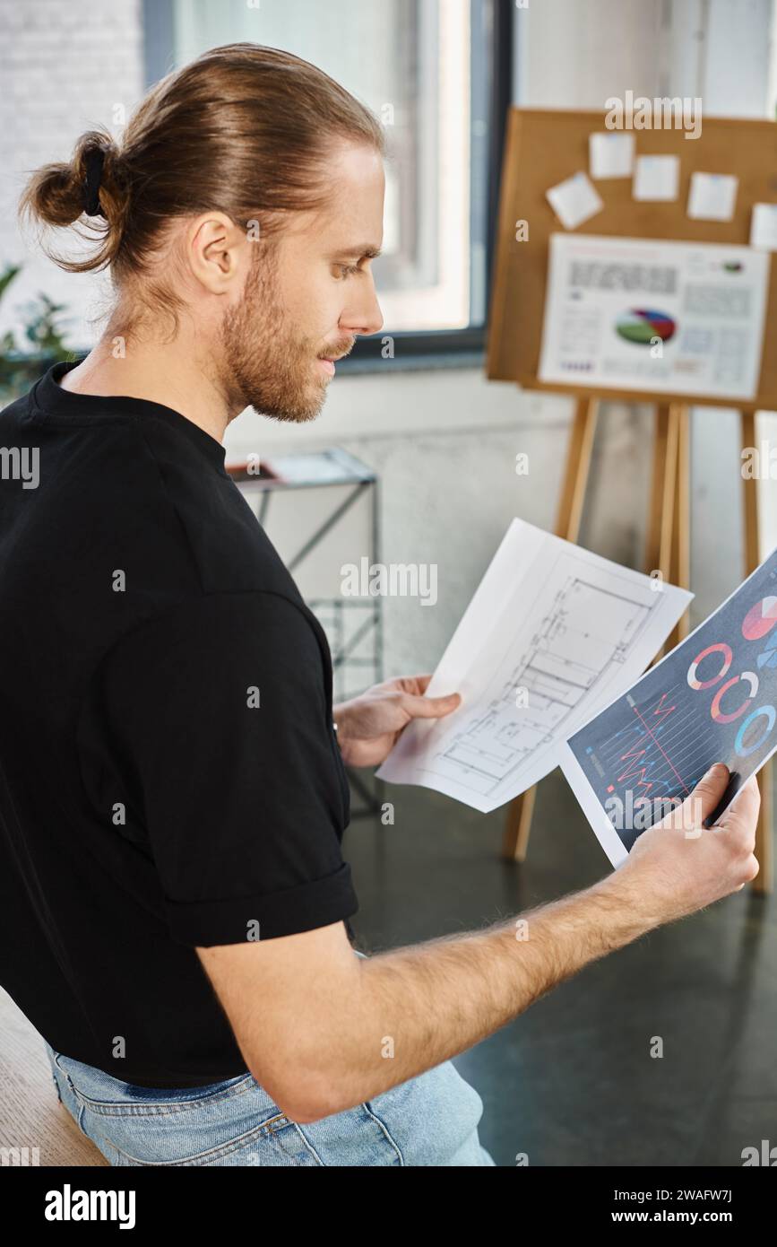 stylish businessman in black t-shirt looking at papers with charts and ...
