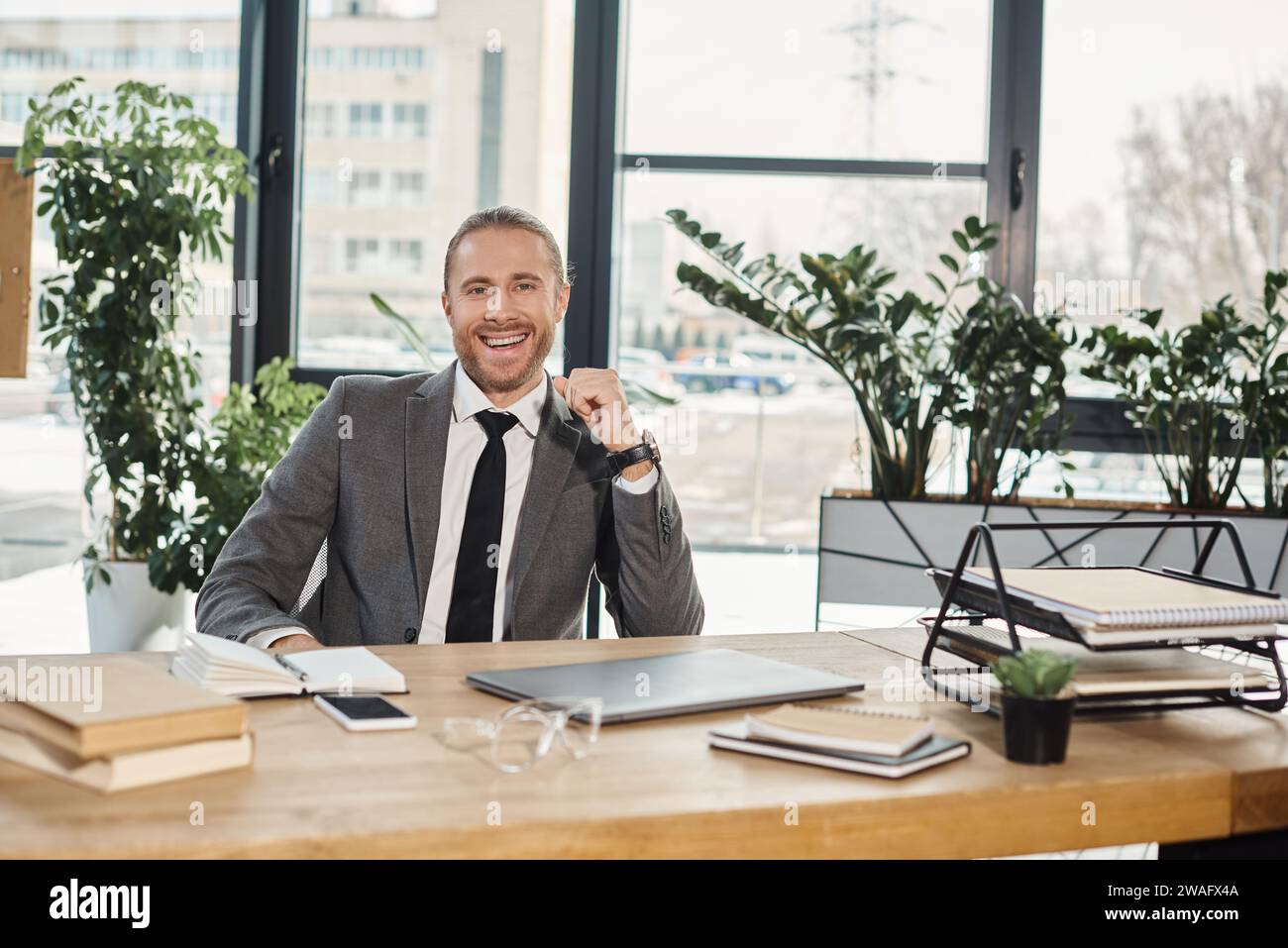 cheerful businessman looking at camera at work desk with documents and ...