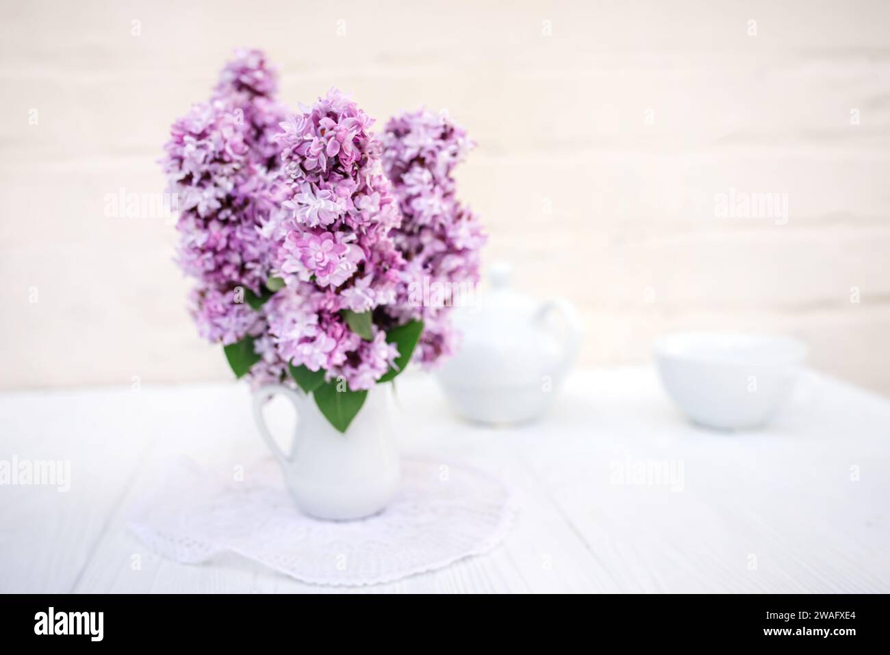 Bouquet of lilacs in a white vase on a served table. Fresh lilac ...