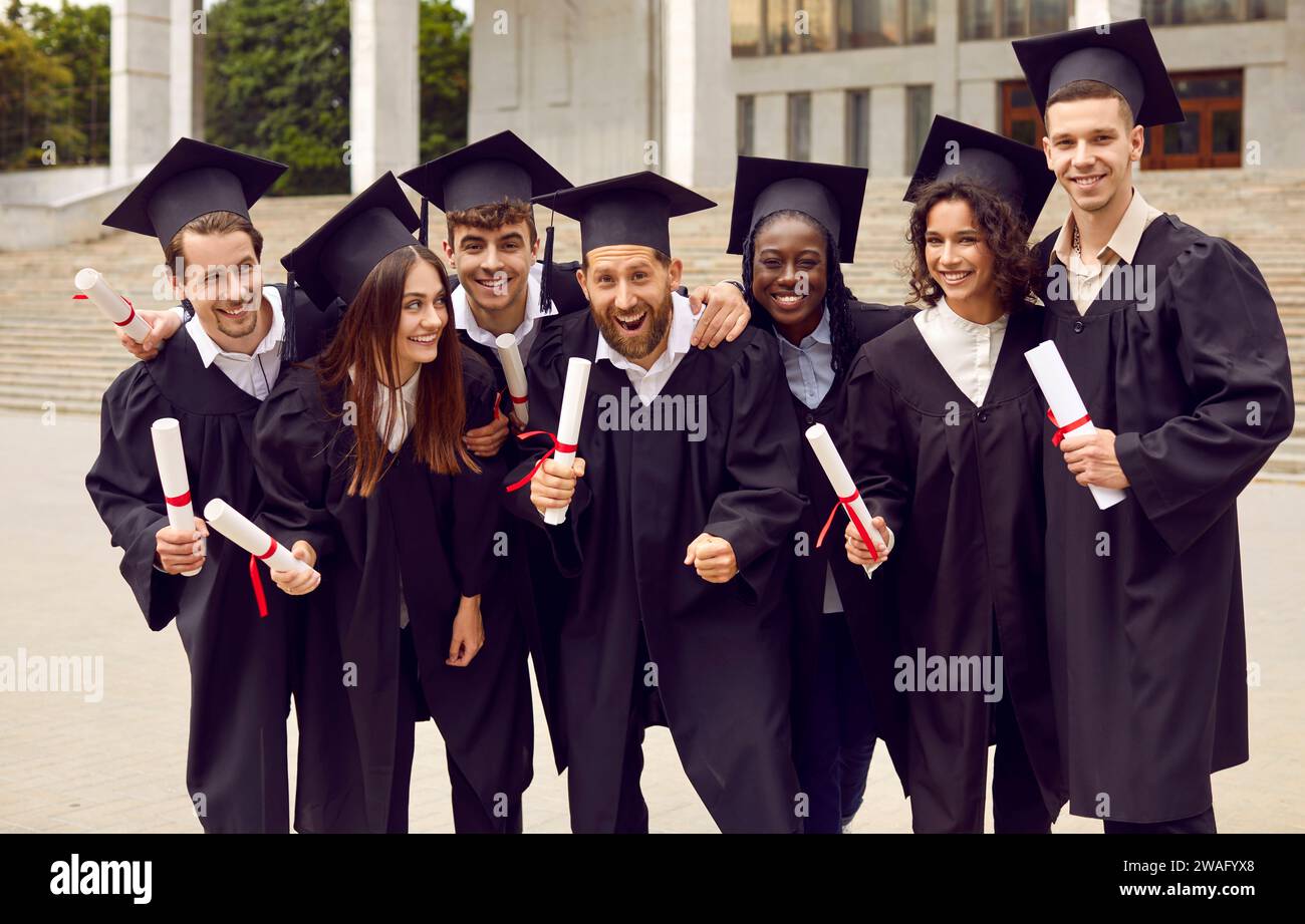 Group of happy diverse university friends in caps and gowns celebrating ...