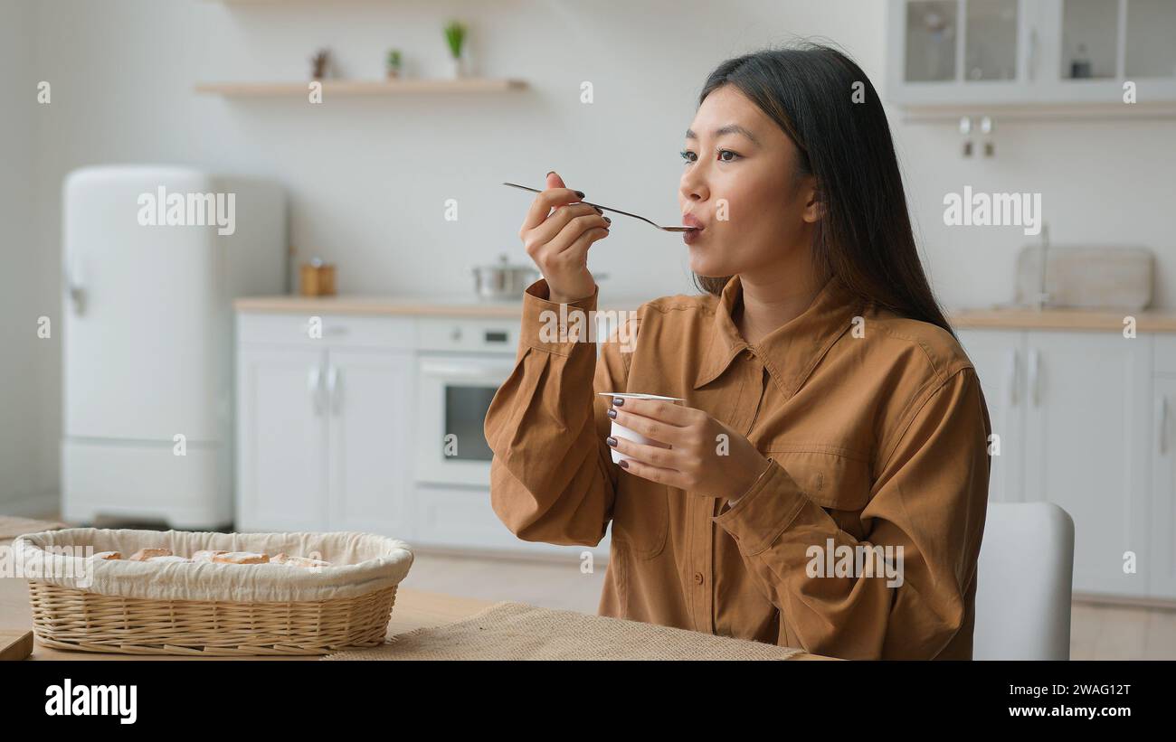Chinese girl eat healthy natural yogurt in domestic kitchen Asian ...