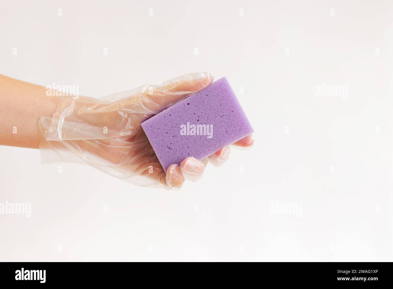 Cleaning the room, sponge in hand close-up. Female hand in a glove with ...