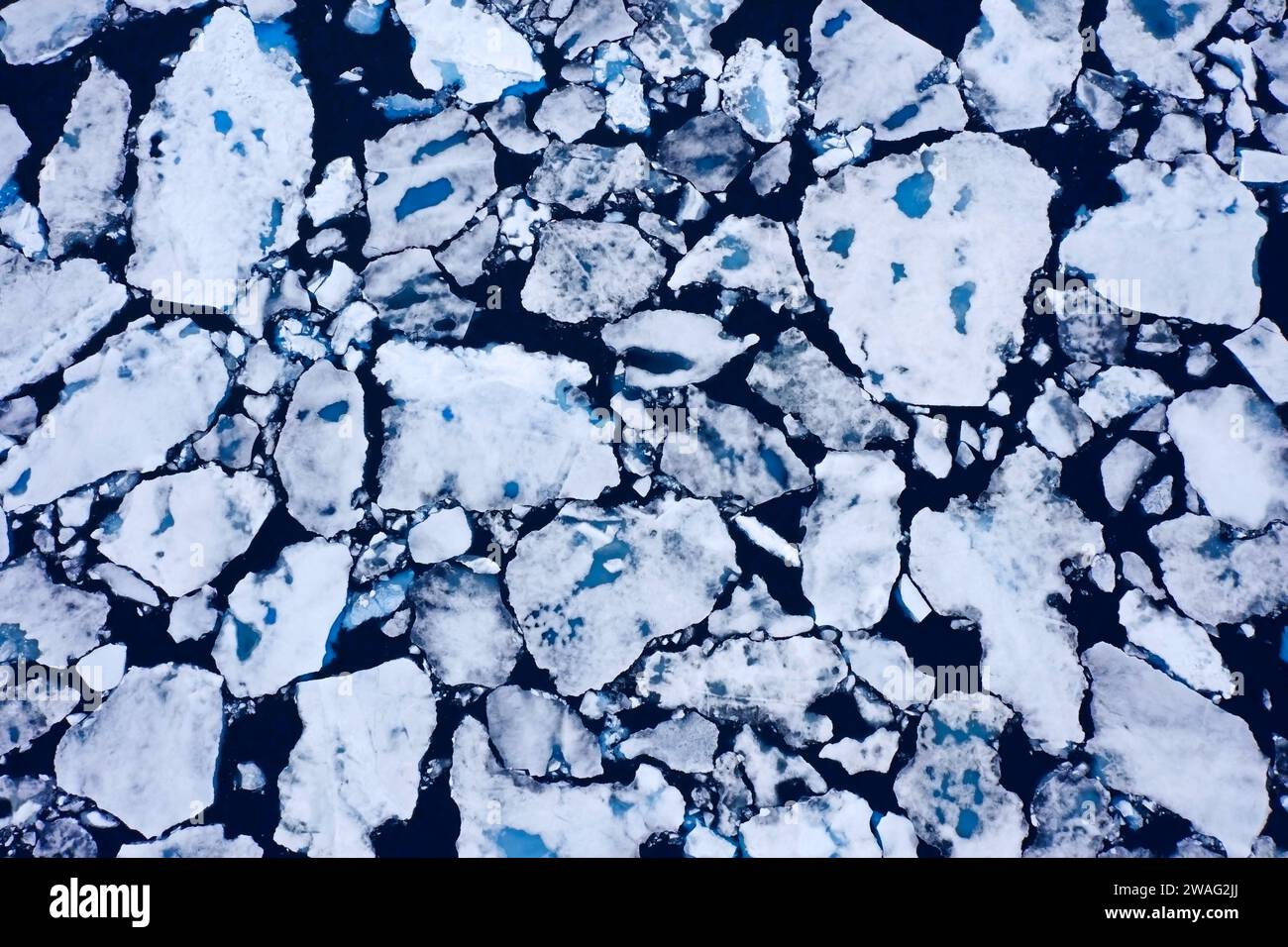 Aerial view over sea ice / drift ice / ice floes with melt ponds ...