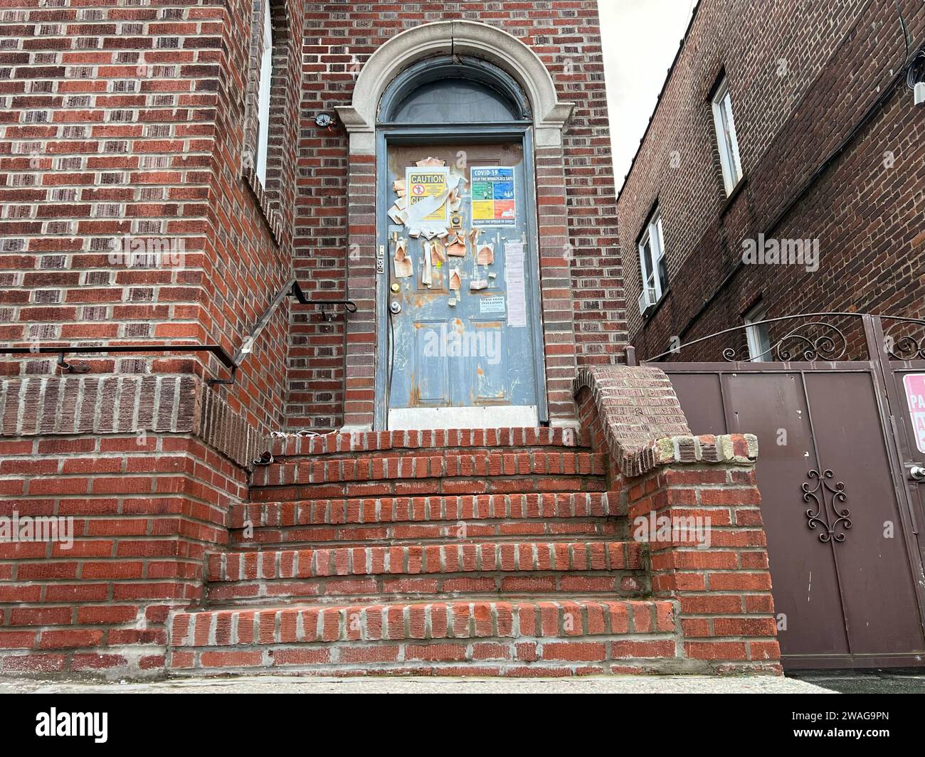 A door of a red brick building with multiple caution signs Stock Photo ...