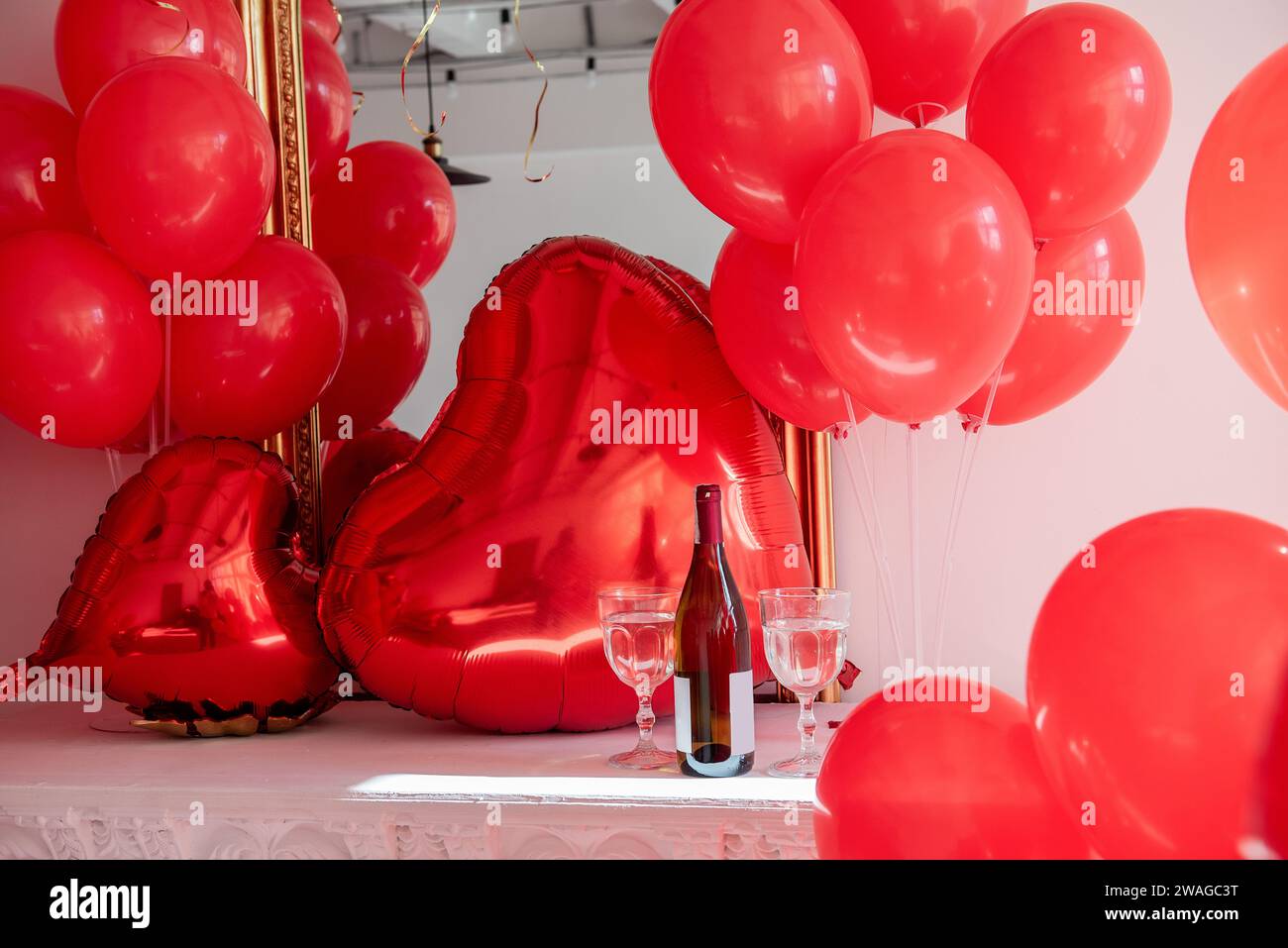 On white table bottle of wine with two glasses among inflatable red ...