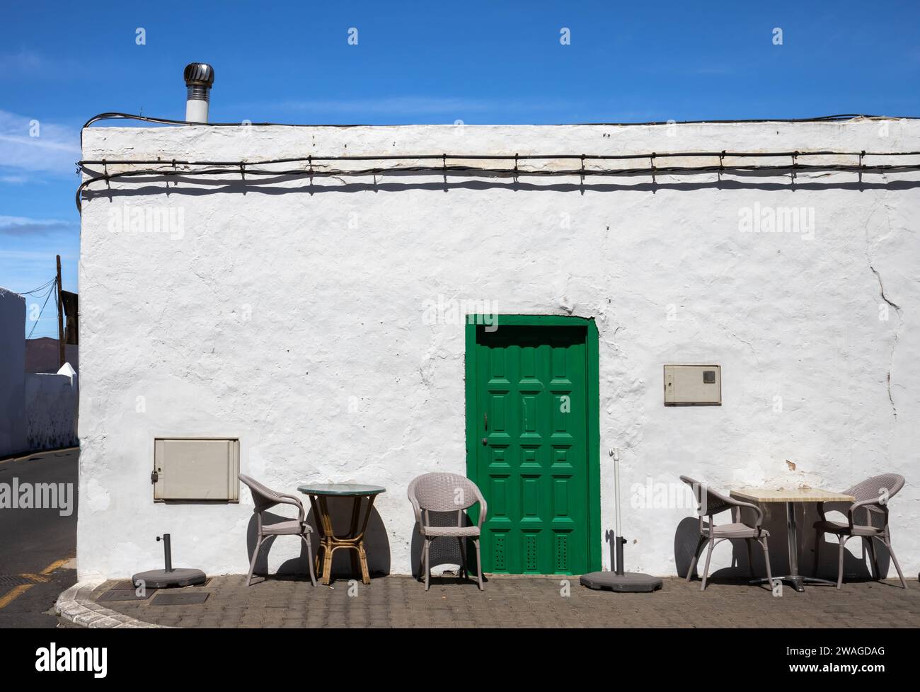 Corner of streets. Two empty tables of a closed cafe in a white ...
