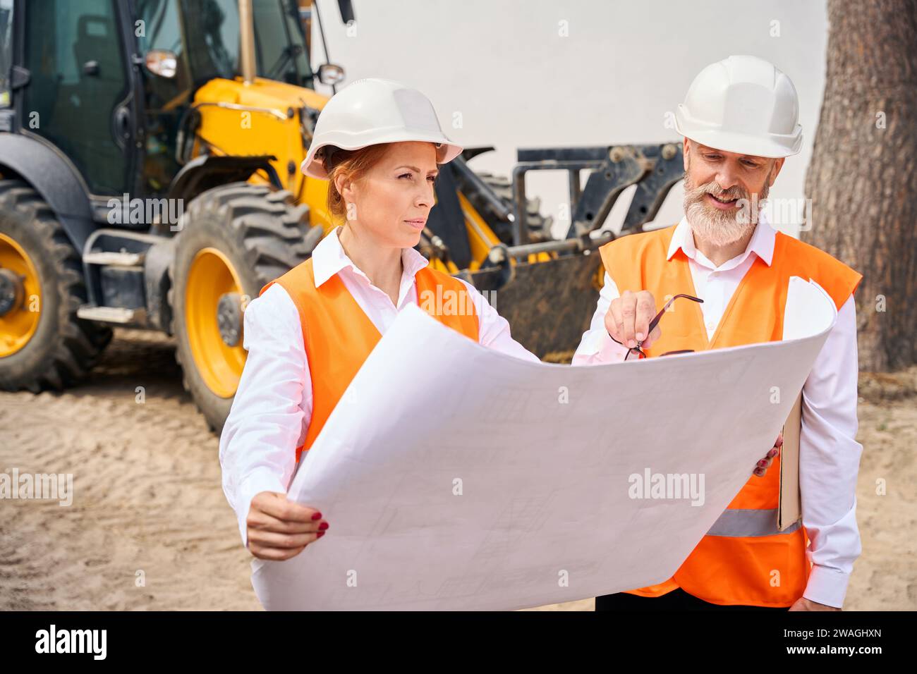 Building inspector and contractor using blueprints during inspection ...