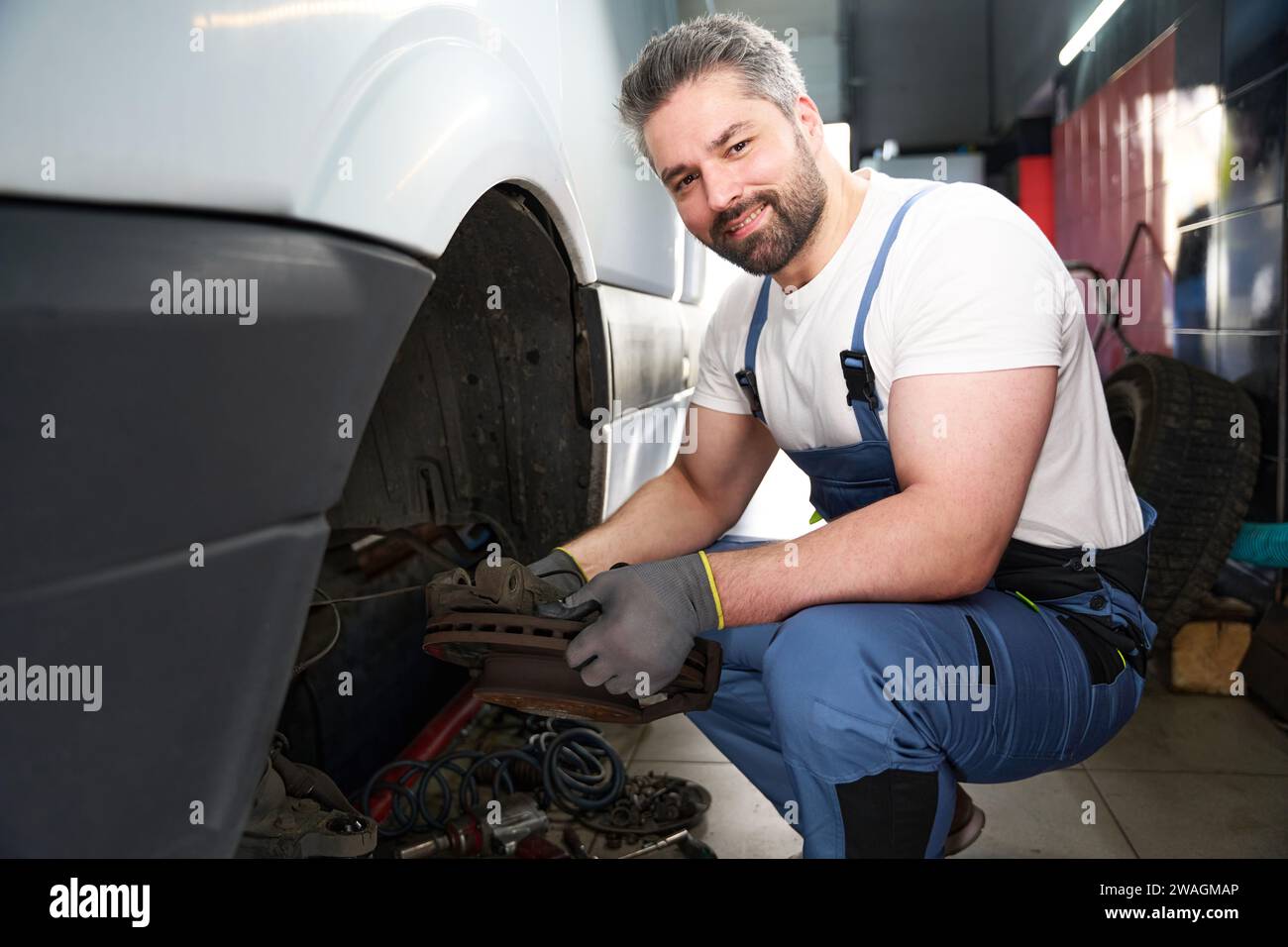 Smiling auto repair worker is posing for camera at work Stock Photo - Alamy