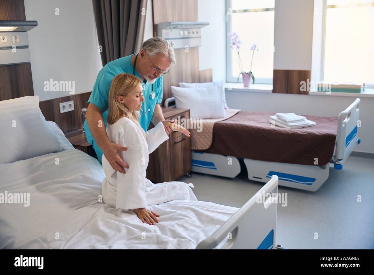 Female patient being lifted by healthcare worker from hospital bed ...