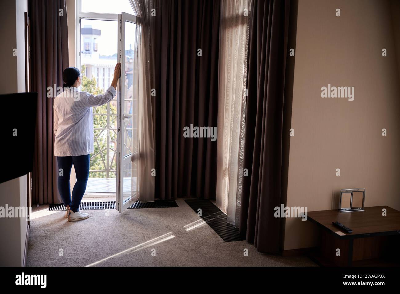Female tourist contemplating city landscape from her suite upon arrival ...