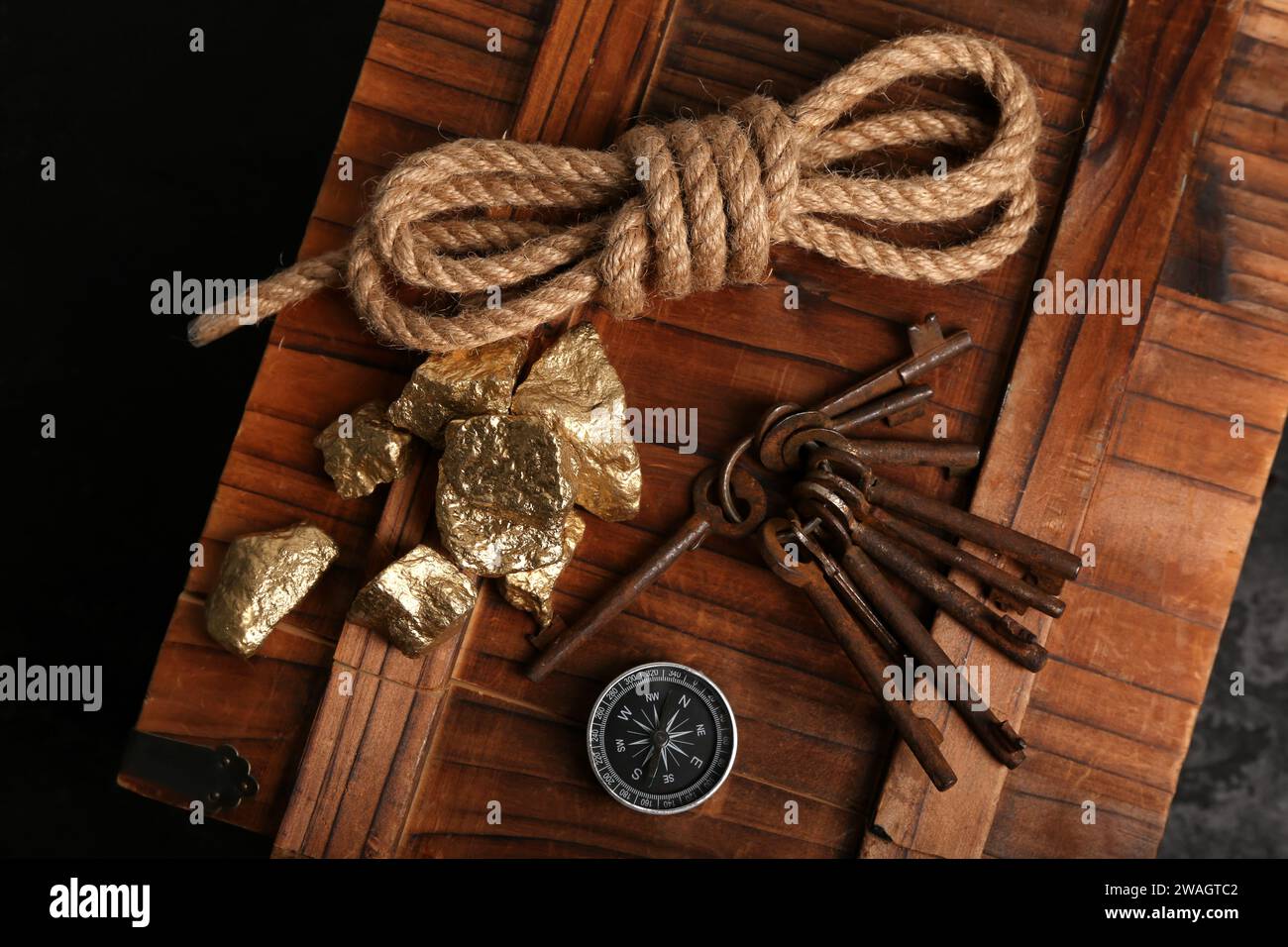 Wooden box with travel equipment and golden nuggets on black background ...