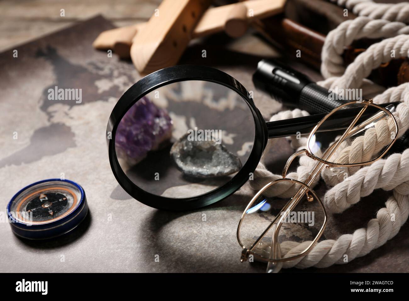 Magnifier with mineral stones, world map and travel equipment on brown ...