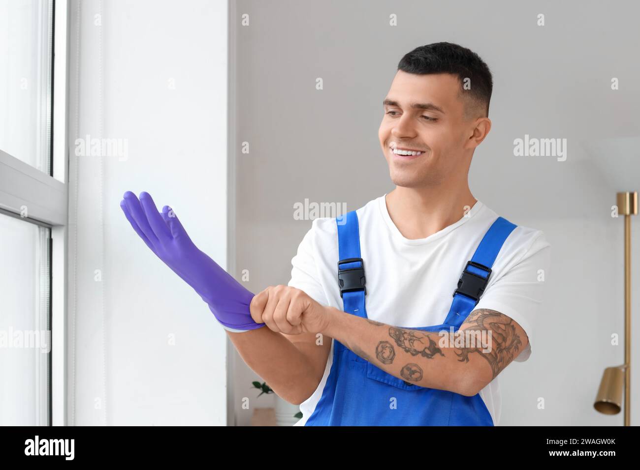 Male janitor putting on rubber glove in room Stock Photo - Alamy