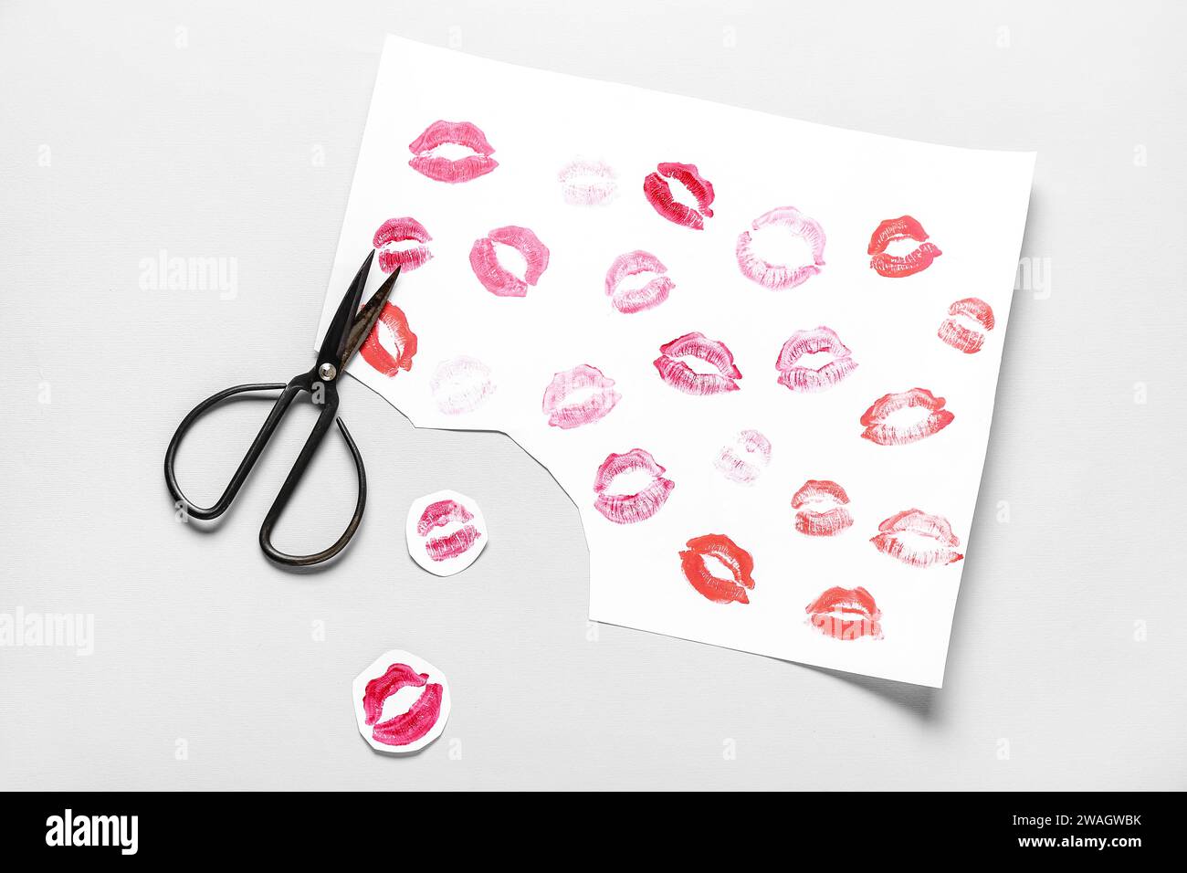 Paper sheet with lipstick kiss marks and scissors on grey background ...
