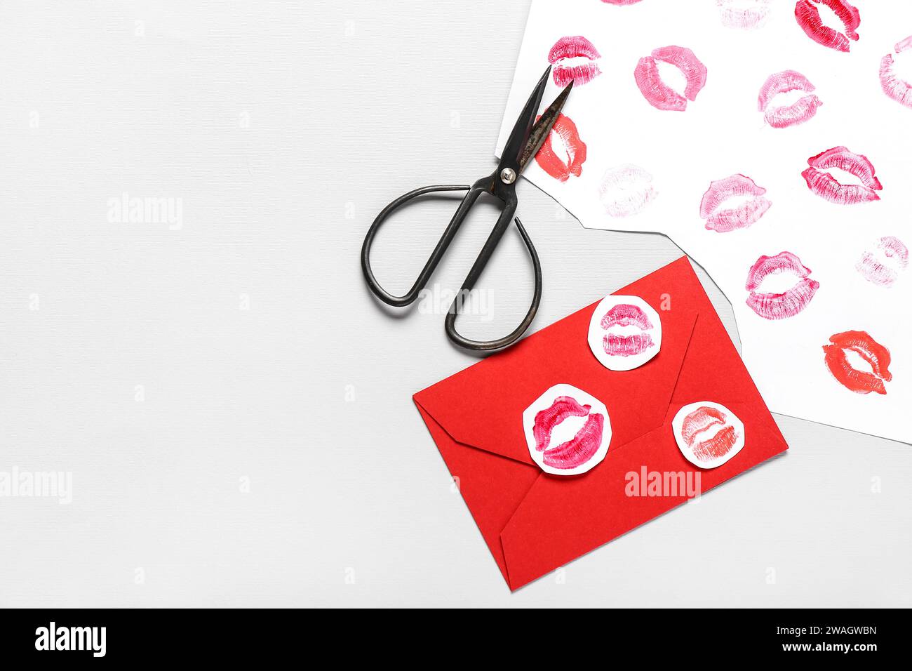 Paper sheet with lipstick kiss marks, envelope and scissors on grey background. Valentine's Day ...