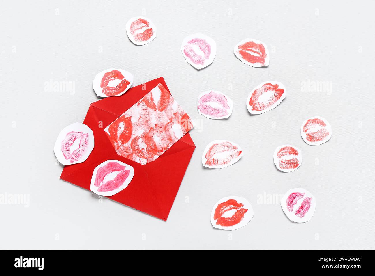 Red envelope with card and lipstick kiss marks on grey background. Valentine's Day celebration ...