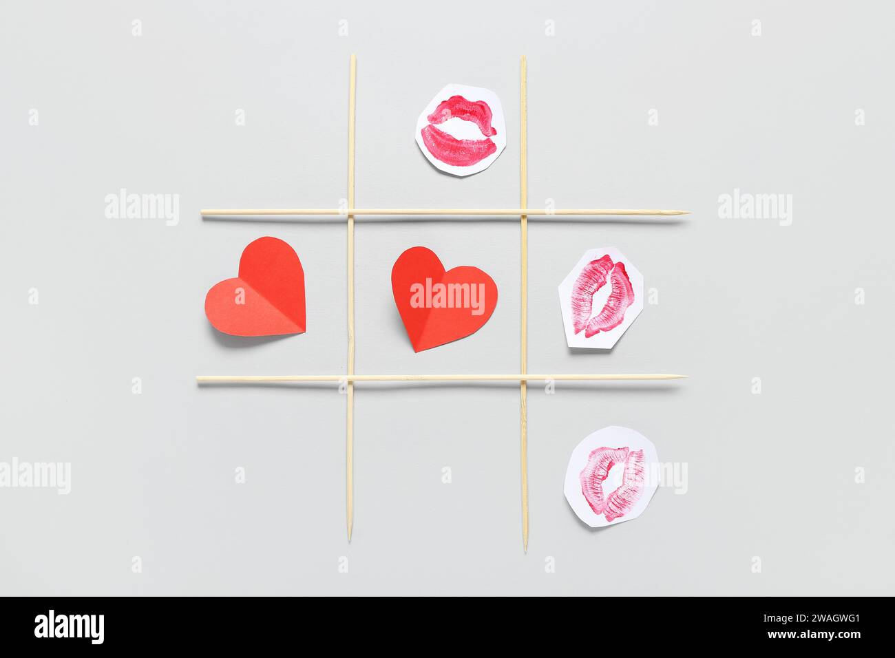 Tic tac toe game with paper hearts and lipstick kiss marks on light ...