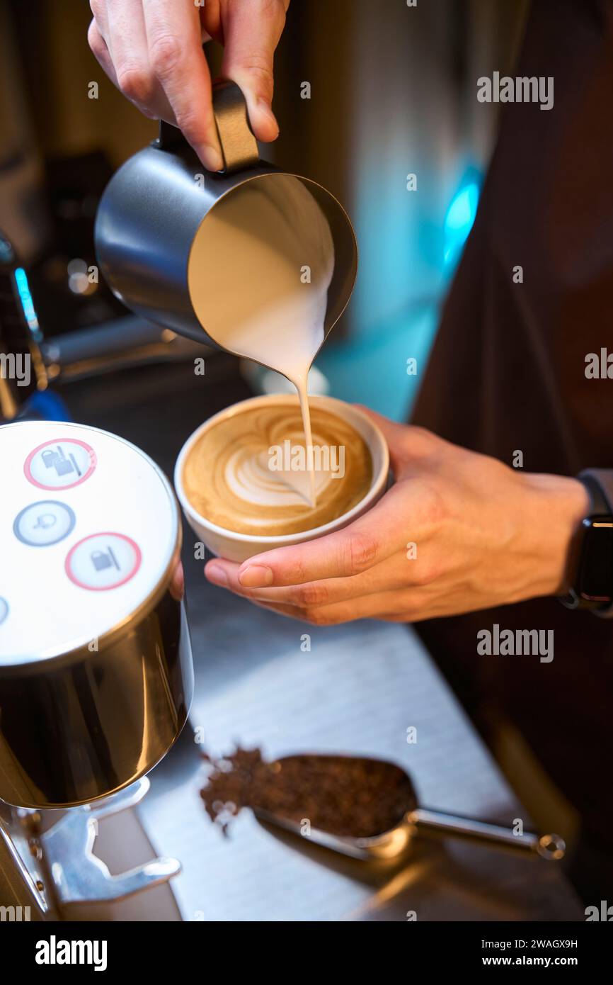 Barista making cappuccino pouring milk for latte art brewing coffee ...