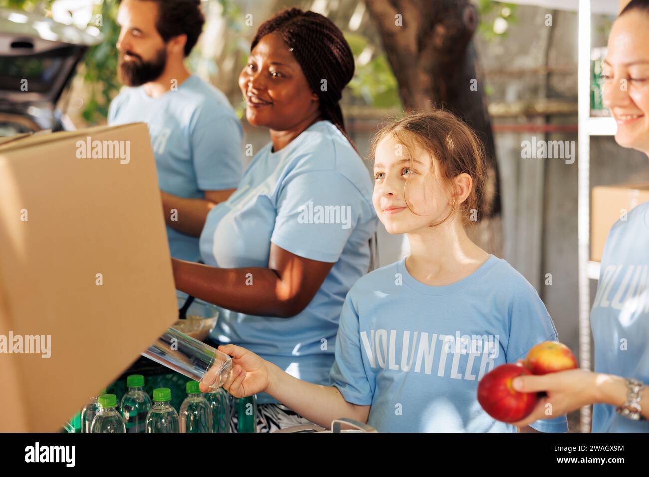 Photo focus on young volunteer girl sharing water and neccesities to ...
