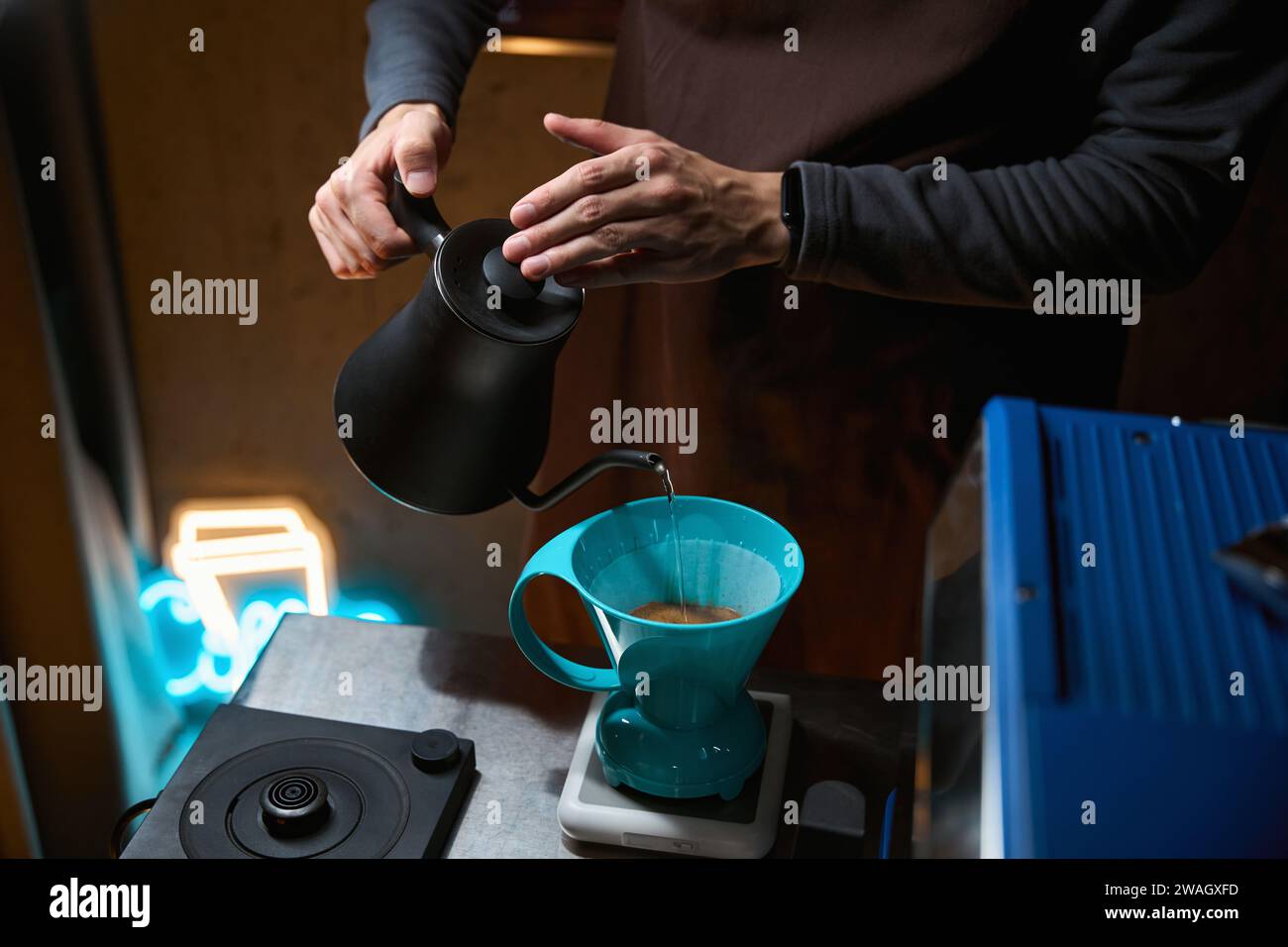 Barista pouring hot water over filter with ground coffee in the funnel ...