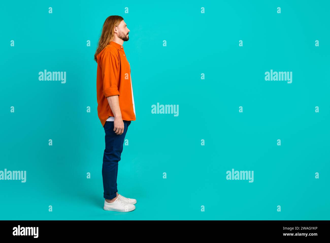 Side profile photo of thin guy in orange shirt and blue pants looking ...
