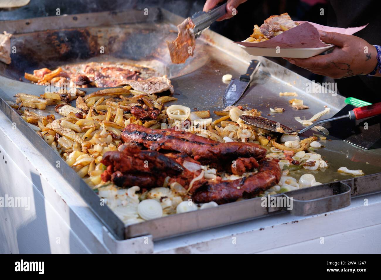 Mexican outdoors food cart frying various meats and fries in skillet at ...