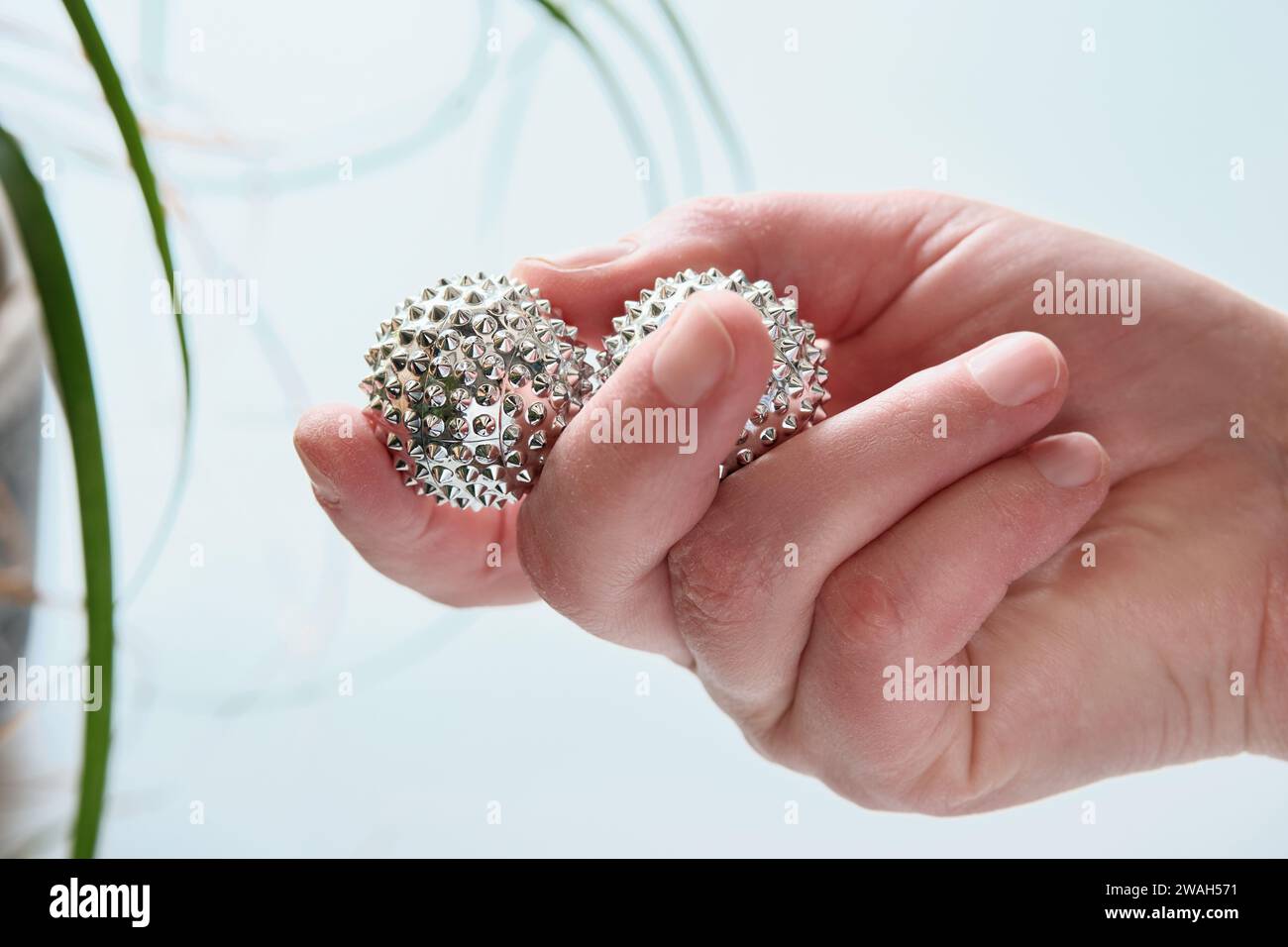 Silver metal magnetic balls in female hand. Spiky tool for hand massage ...