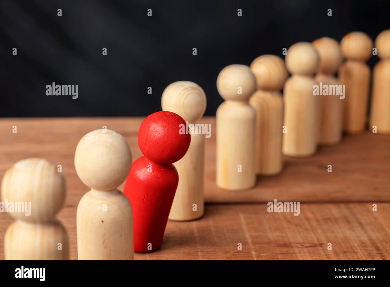 Red wooden figures stand out from the crowd of wooden figures ...
