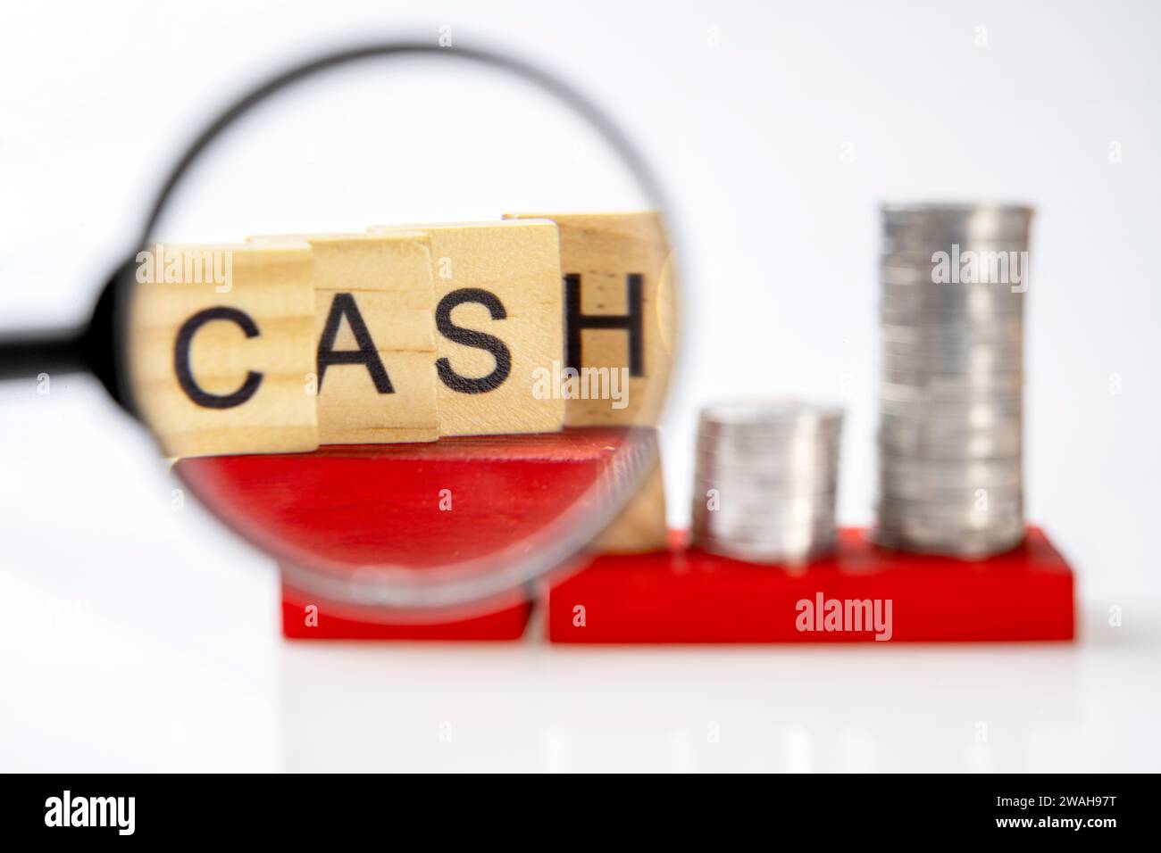 The magnifying glass focuses on a wooden cube with cash words with a ...